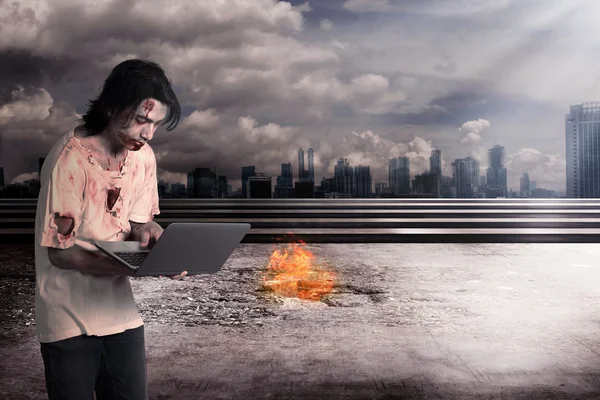 Creepy male zombie typing with laptop - Stock Image - Everypixel