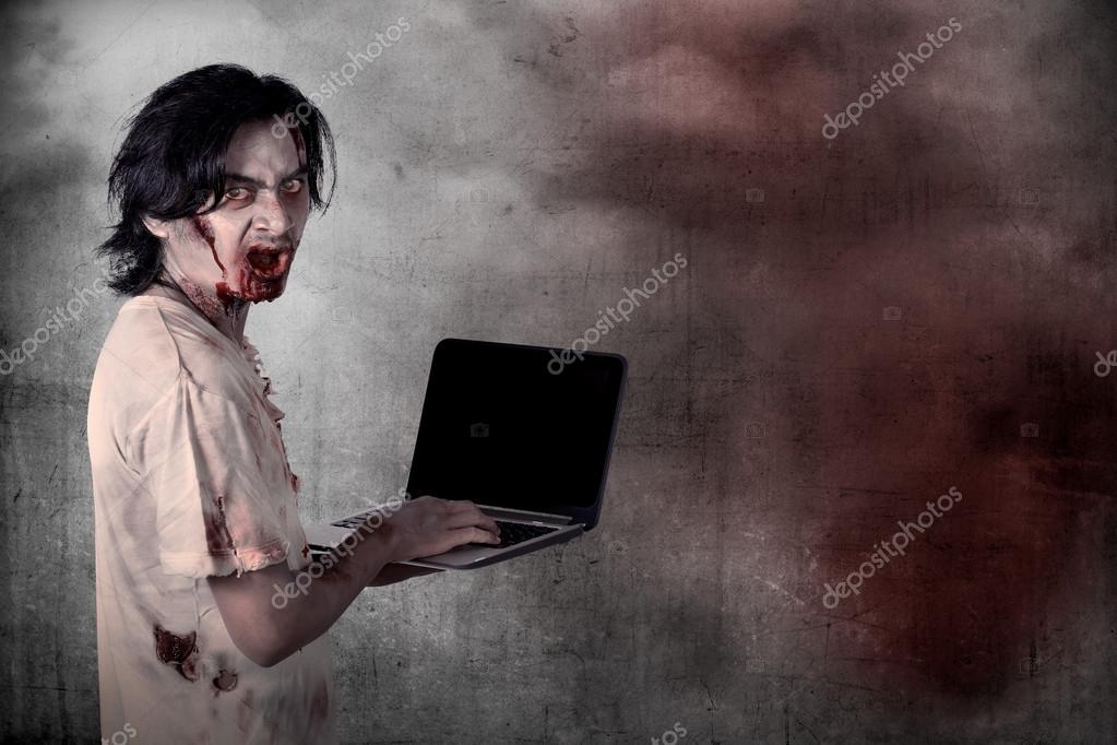 Scary male zombie typing with laptop Stock Photo by ©leolintang 82823854