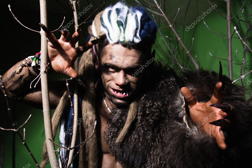 Werewolf with long nails and crooked teeth among the branches of ...