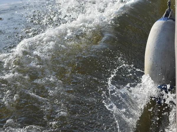 Rushing water quickly bursts out from under the bow of the boat ...