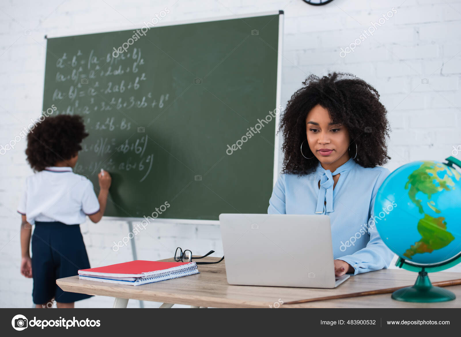 African American Teacher Using Laptop While Pupil Writing Chalkboard ...