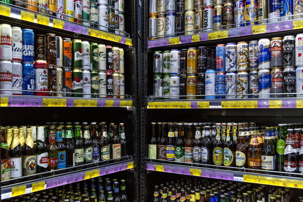 Botellas y latas de cerveza en los estantes de la tienda. Gran elección ...