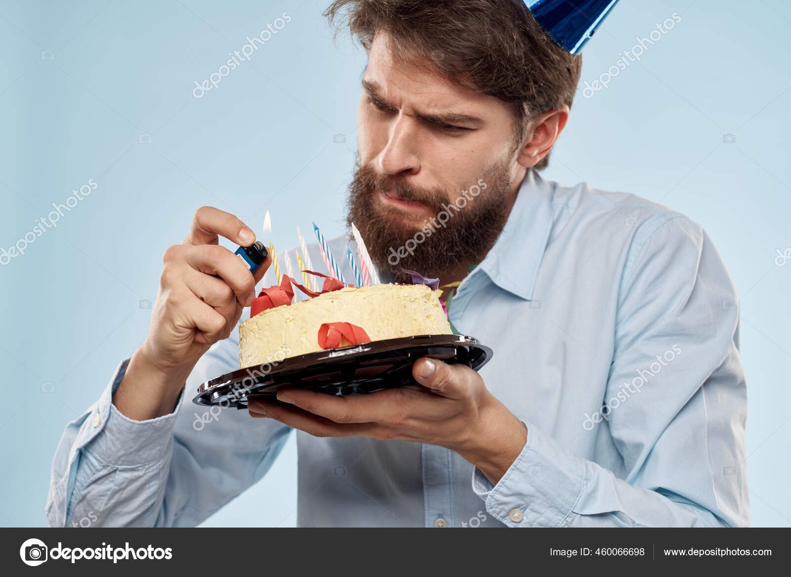 A man in a shirt with a cake in his hands and a festive cap on his head ...