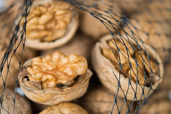 Close-up of partly peeled walnuts in black plastic net package. Group ...