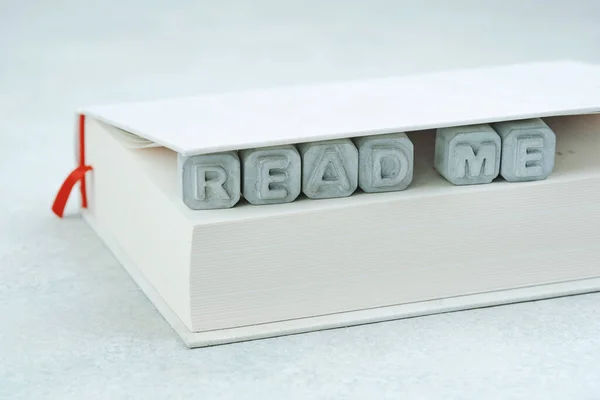 Text Read Me made of gray concrete letters on a white book. Motivation ...