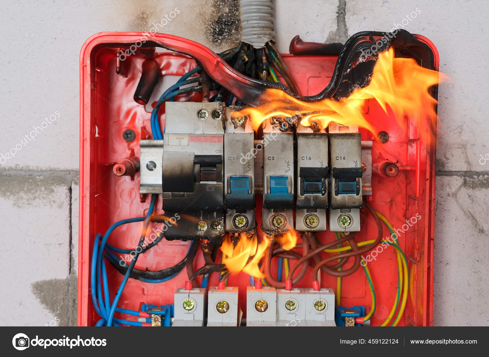 Burning switchboard from overload or short circuit on wall closeup ...