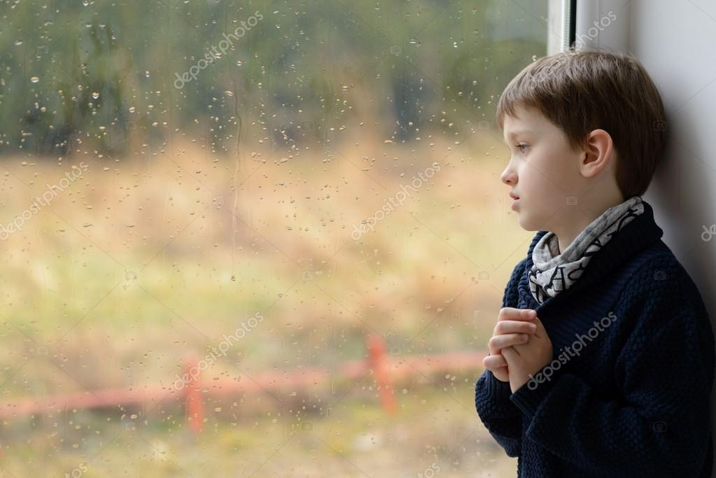 Thoughtful little boy looking through the window. Stock Photo by ...