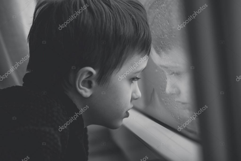 Little boy waiting by window for stop raining - black and white Stock ...