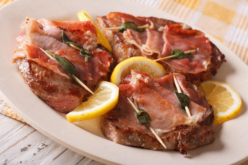 Italian cuisine: beef saltimbocca with lemon close up. horizonta Stock ...