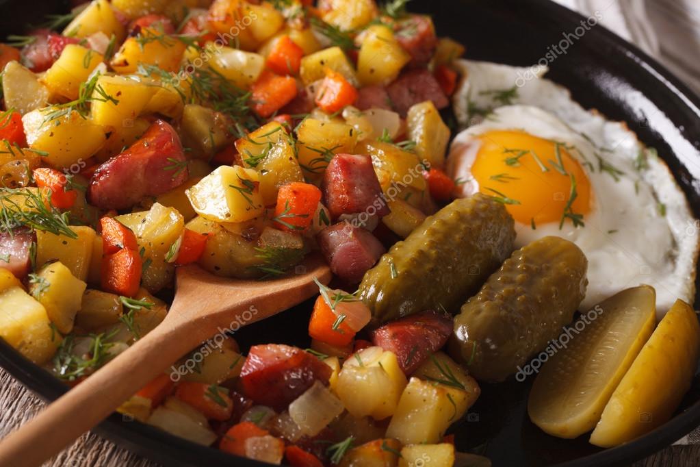 Scandinavian breakfast: pyttipanna with fried eggs and pickled c ...