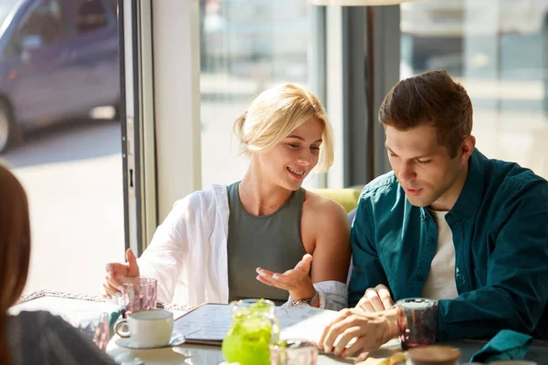 happy young couple enjoying while choosing an order from menu in modern ...