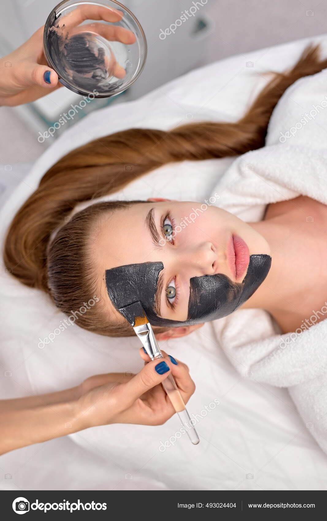 Procedure for applying black mask on face of beautiful woman, top view ...