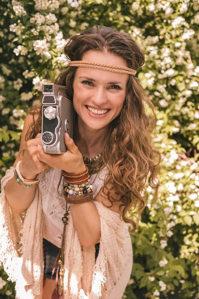happy boho young woman among flowers with retro camera - Stock Image ...