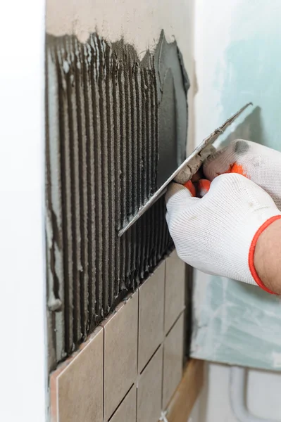Worker putting tiles on the wall in the kitchen. - Stock Image - Everypixel