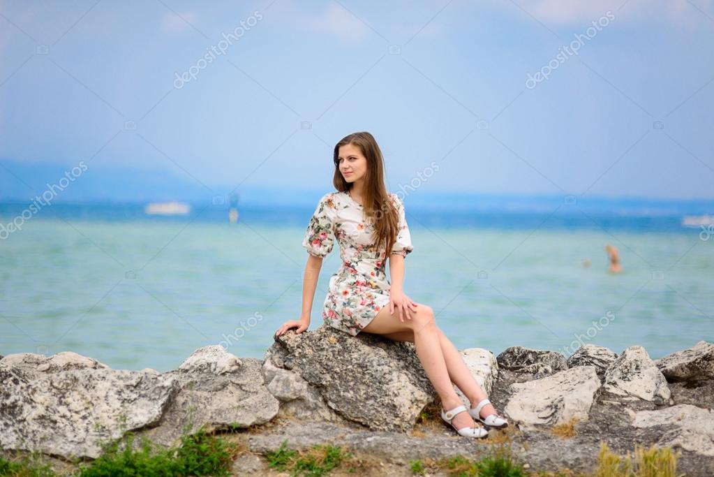 Beautiful woman sitting on rock over sea Stock Photo by ...