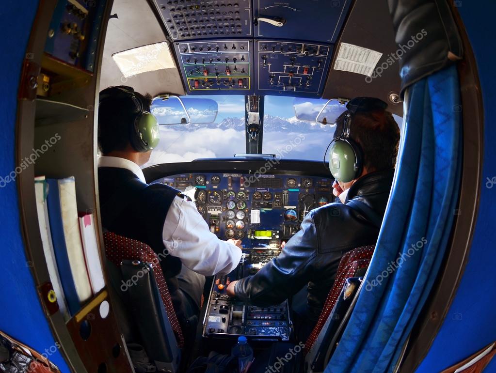 The cabin of the old passenger plane with pilots, mountains and sky ...