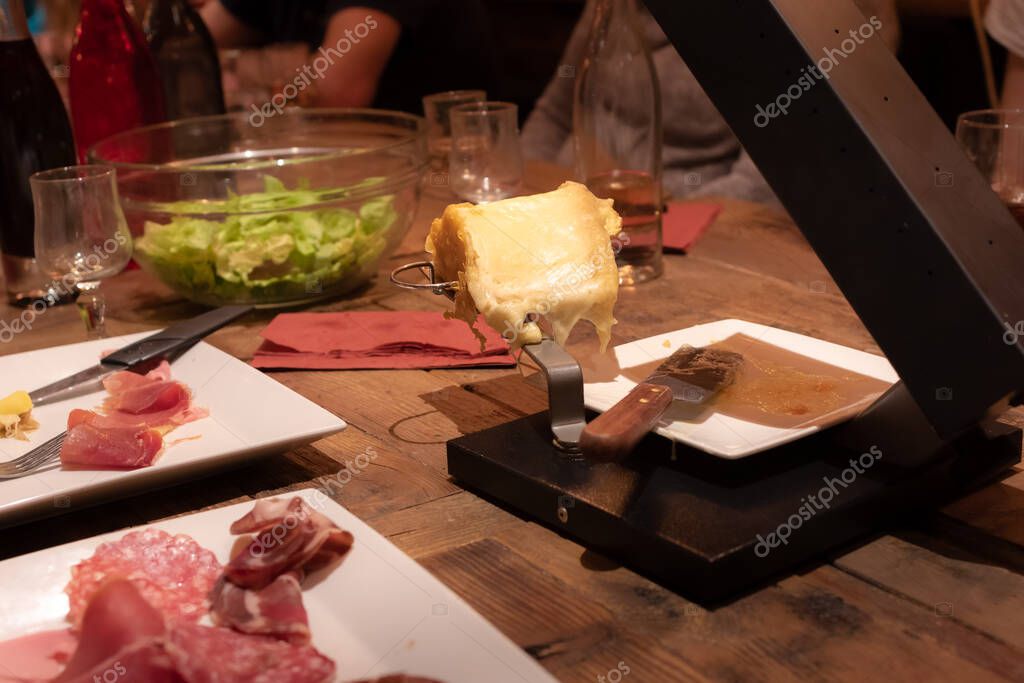 Cena tradicional de raclette en un restaurante, raspando queso ...