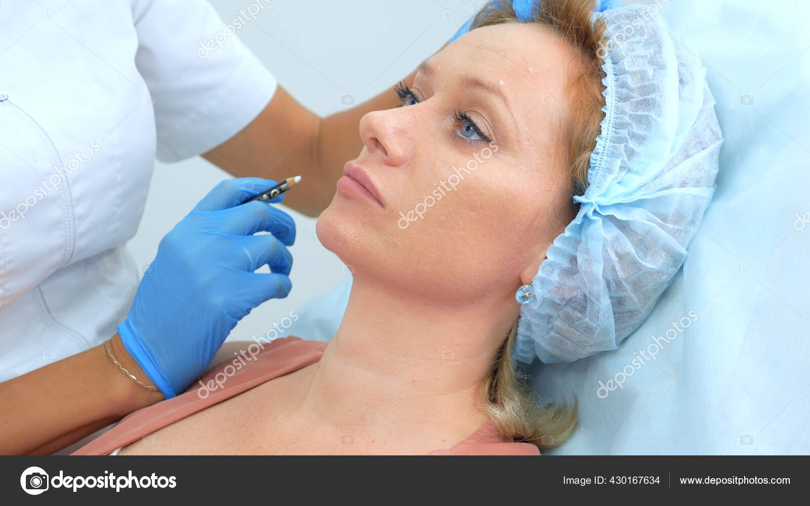 The beautician marks the injection points on the womans face with a ...