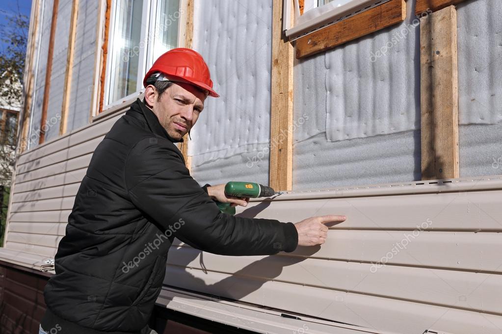 A worker installs panels beige siding on the facade — Stock Photo ...