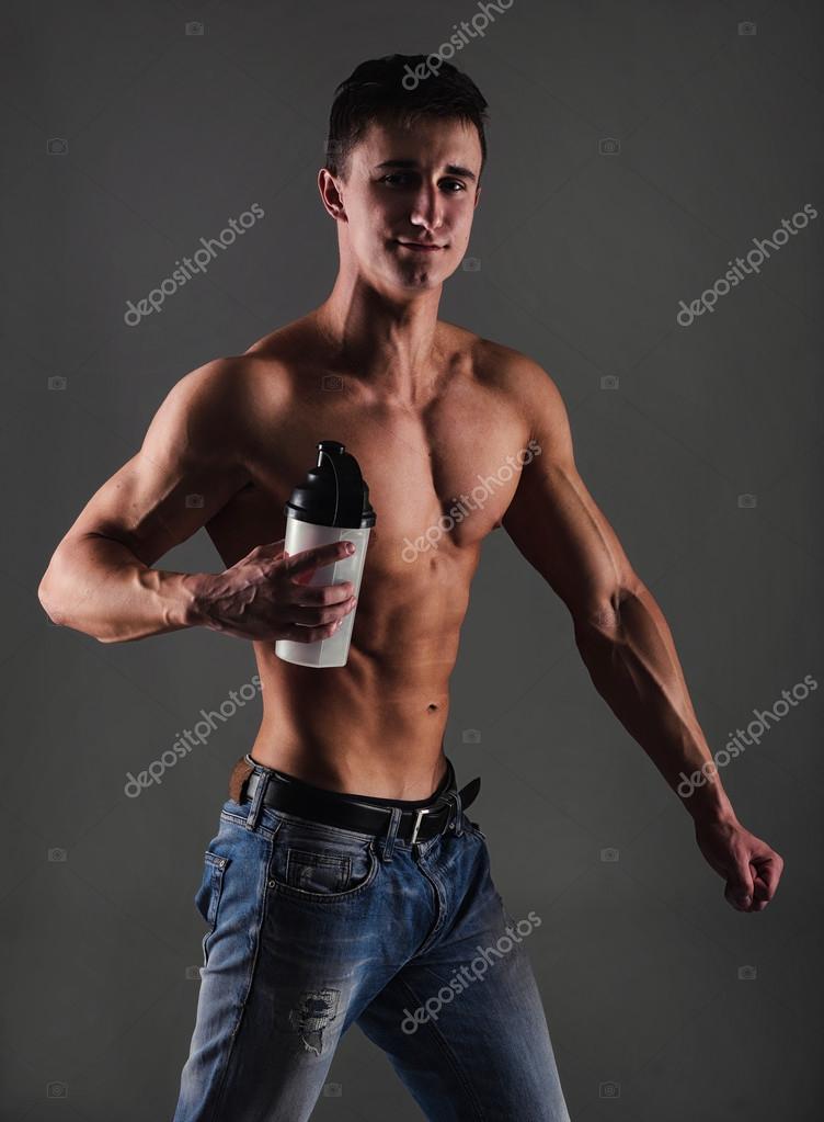 Man bodybuilder posing on gray background Man is holding a shaker for ...