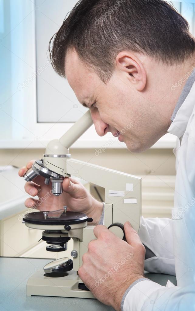 Scientist looking through microscope in laboratory Stock Photo by ...