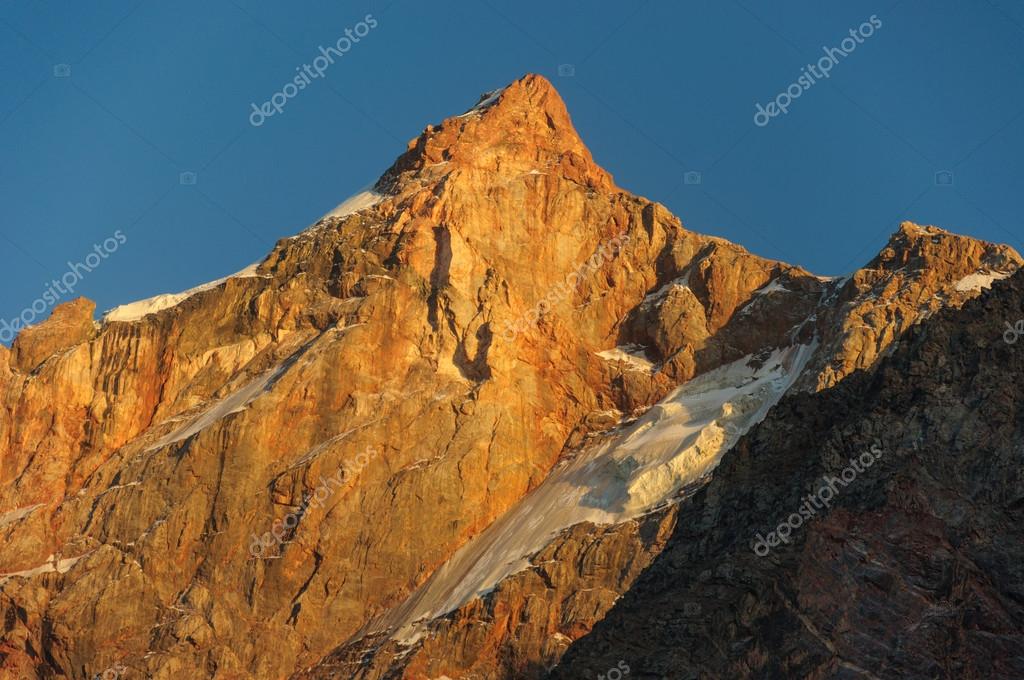 Pico de montaña escarlata de altura en rayos del atardecer 2022