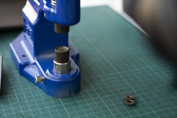Artisan using hand press for setting snaps in leather for makes a ...
