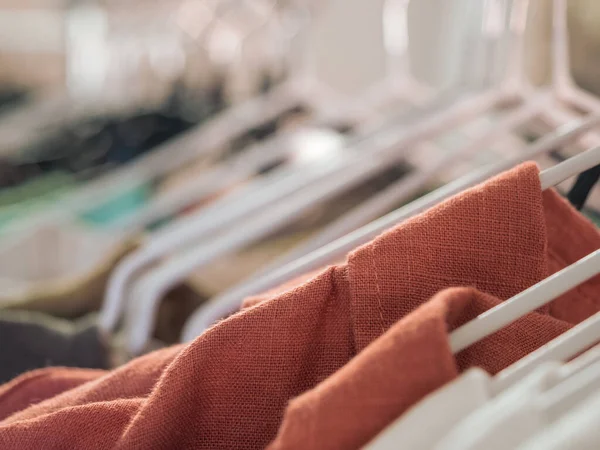 Things made of natural linen in different colors hang on hangers in the ...