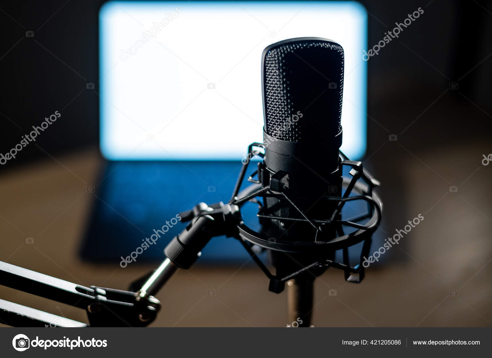Professional microphone and laptop with white screen in the dark ...