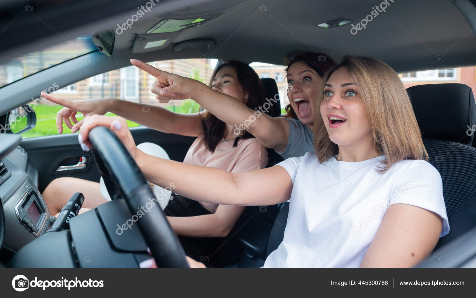Three friends go on a trip. Caucasian women drive in a car and point ...