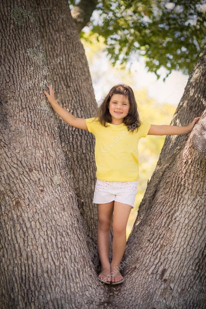 Young girl standing on tree trunk Stock Photo by ©Wavebreakmedia 112919844