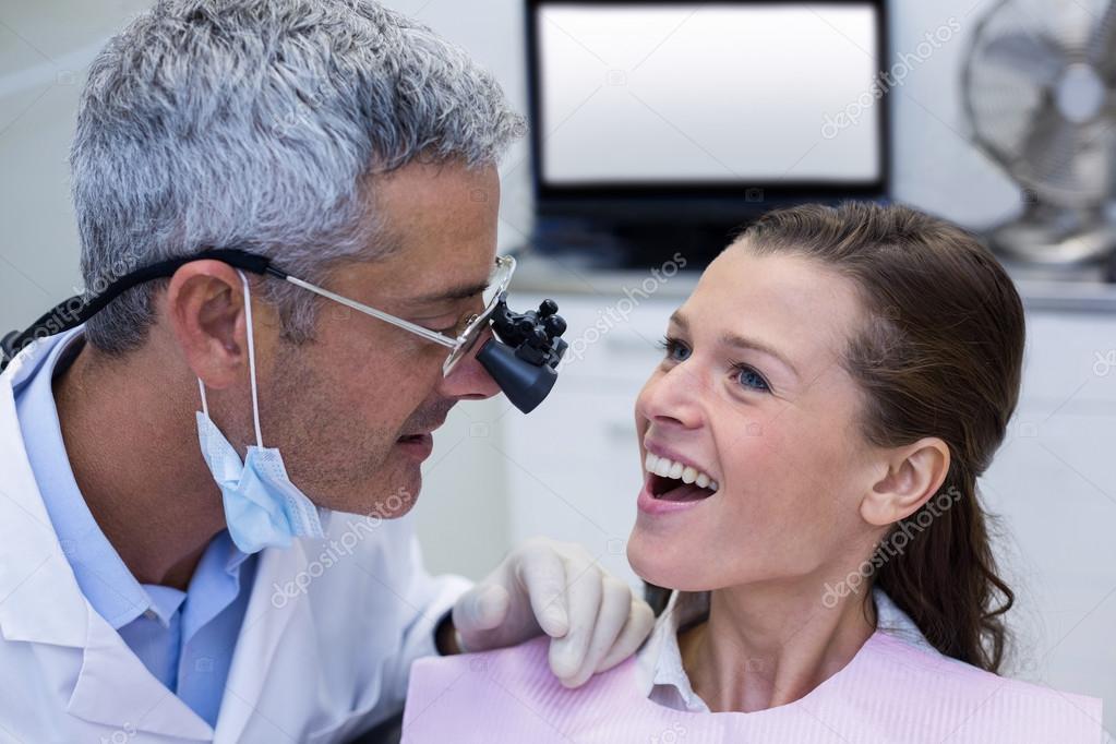 Dentist examining a female patient with dental loupes — Stock Photo ...