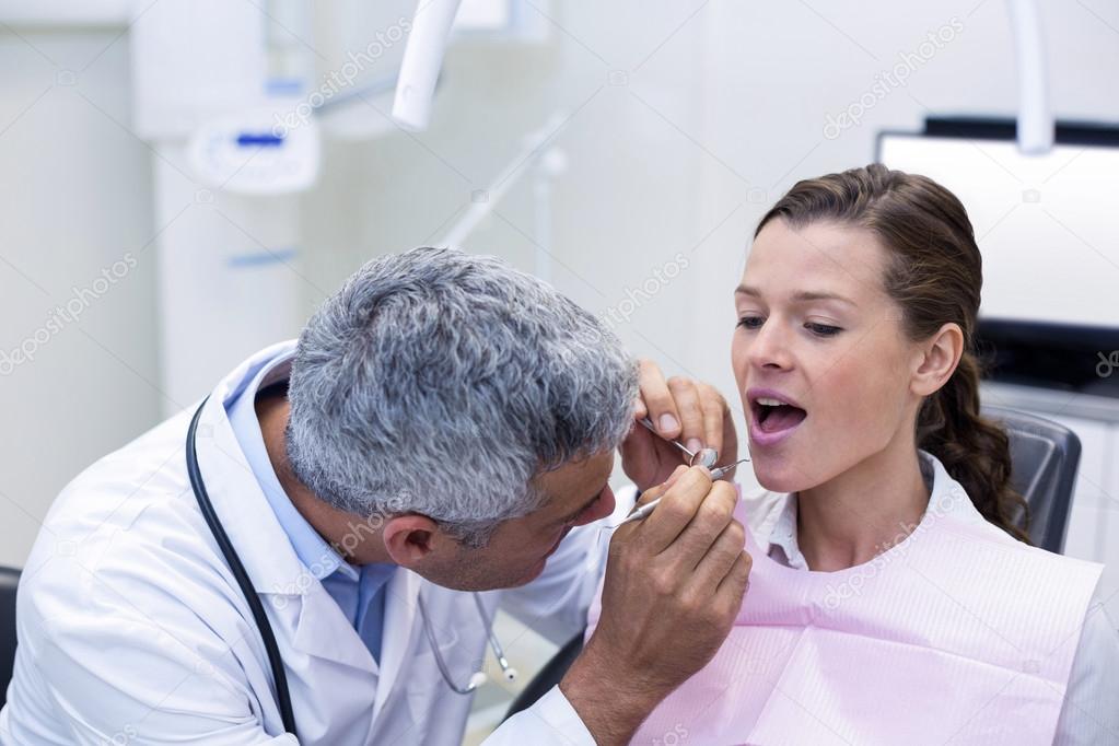 Dentist examining a female patient with tools — Stock Photo ...