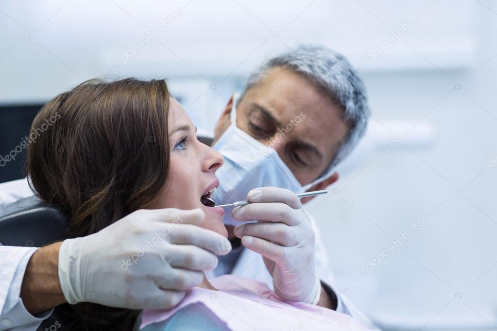 Dentist examining a female patient with tools — Stock Photo ...
