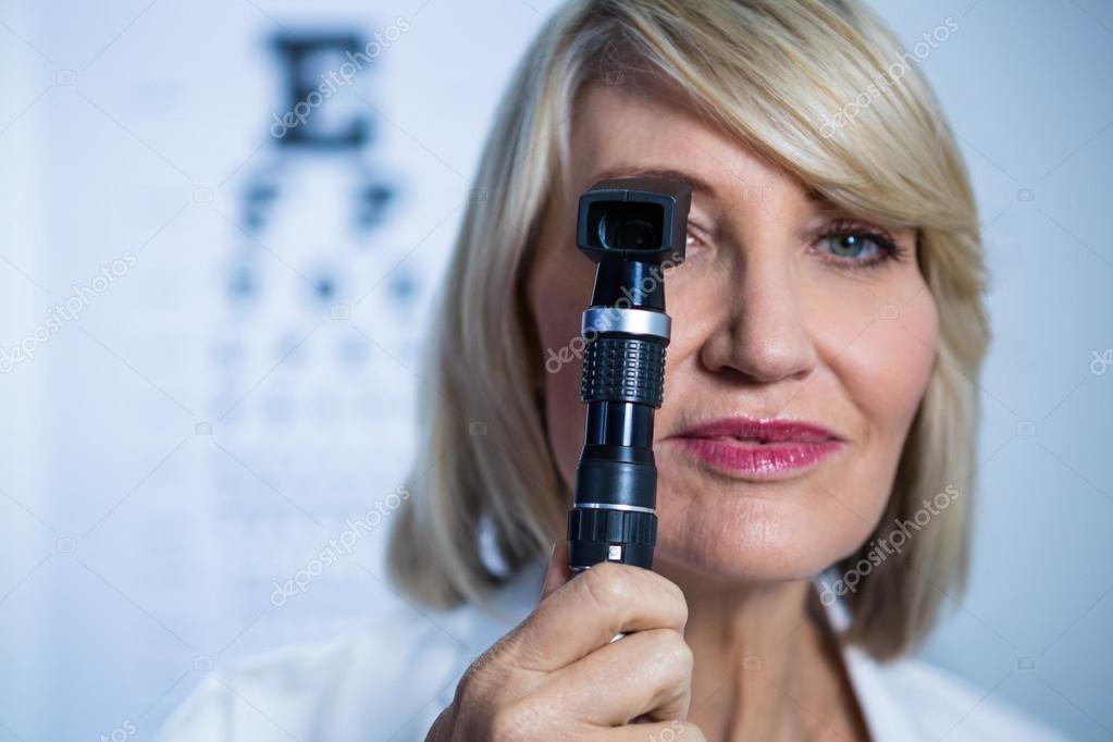 Female optometrist looking through ophthalmoscope Stock Photo by ...