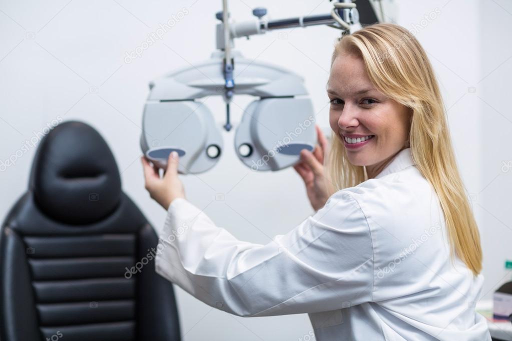 Smiling female optometrist adjusting phoropter Stock Photo by ...