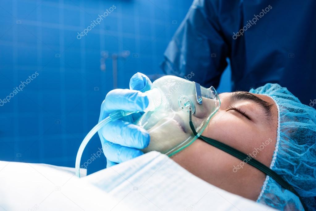Surgeon placing an oxygen mask on face of patient Stock Photo by ...