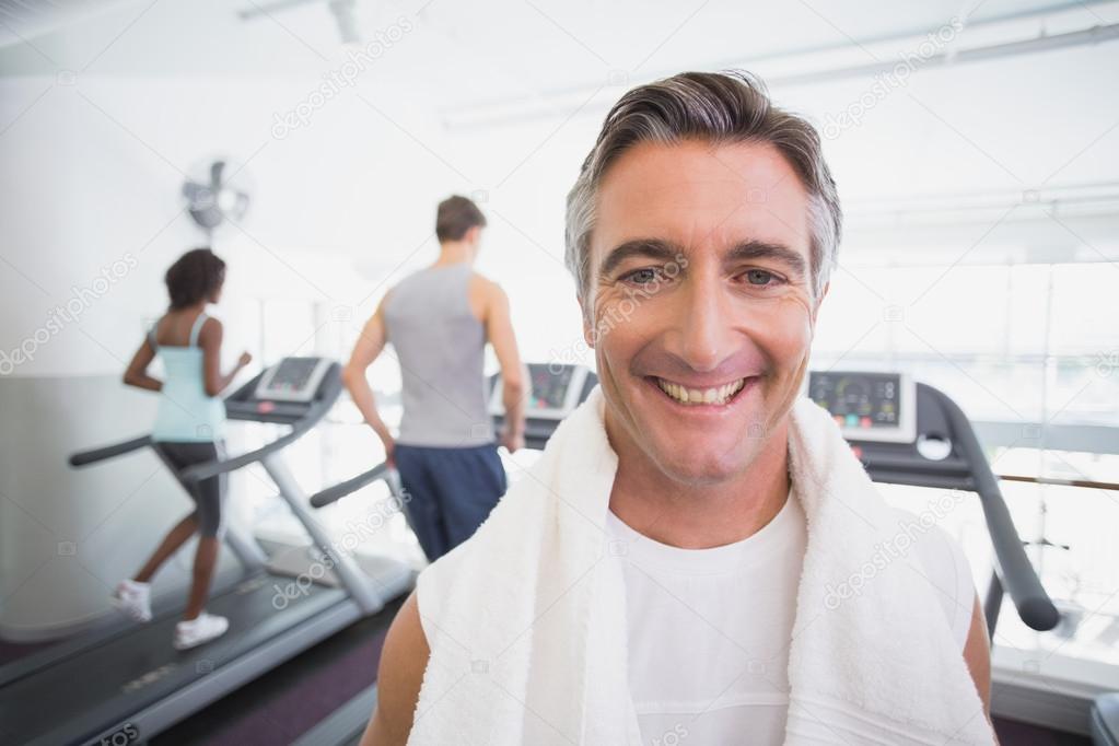 Fit man smiling at camera beside treadmills Stock Photo by ...