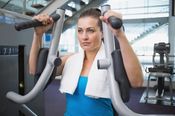 Fit brunette using weights machine for arms - Stock Image - Everypixel