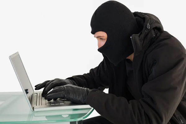 Robber at desk hacking a laptop Stock Photo by ©Wavebreakmedia 60962513