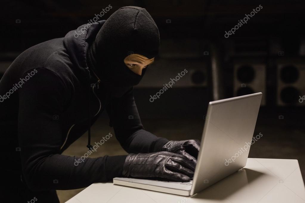 Robber at desk hacking a laptop Stock Photo by ©Wavebreakmedia 60962513