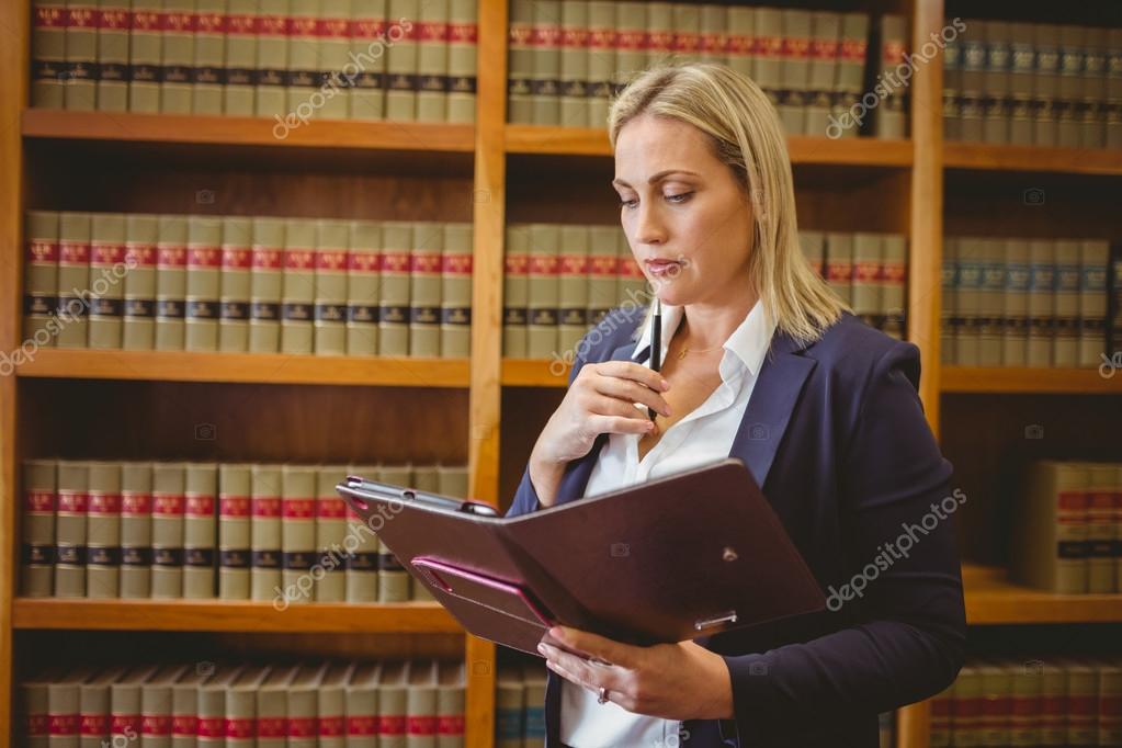 Thinking female librarian holding textbook — Stock Photo ...