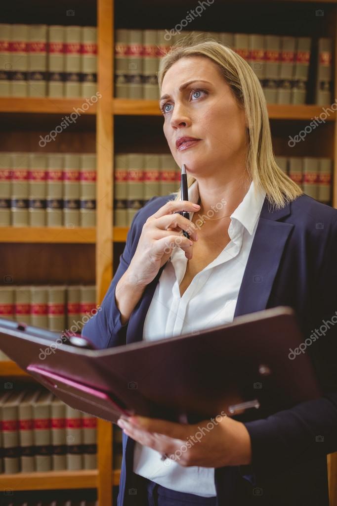 Thinking female librarian holding textbook — Stock Photo ...