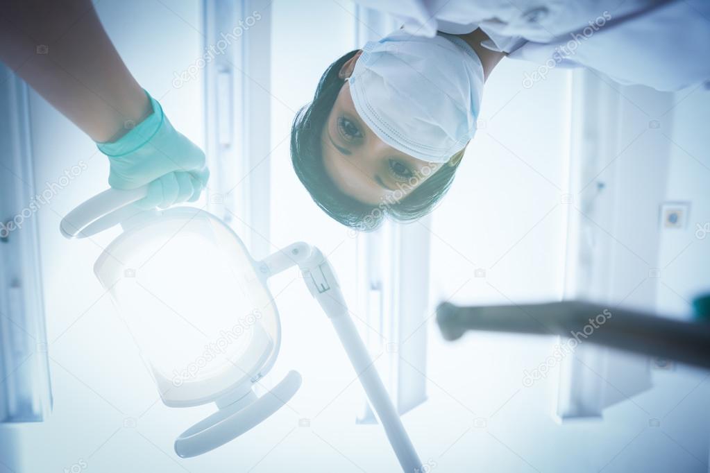 Female dentist adjusting light Stock Photo by ©Wavebreakmedia 65284963