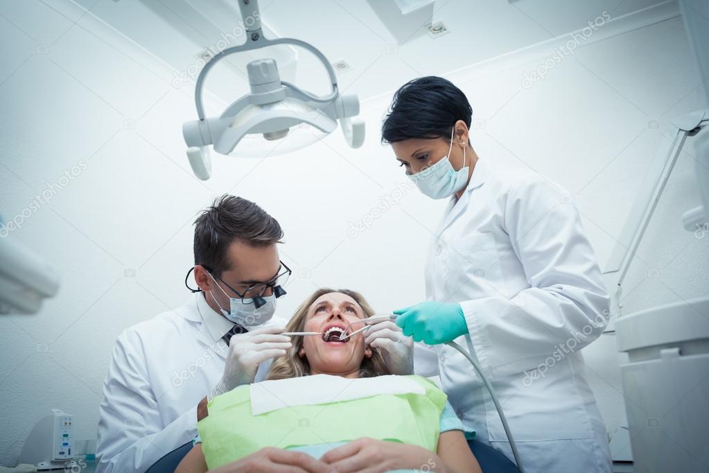 Dentista con asistente examinando los dientes de las mujeres — Foto de ...