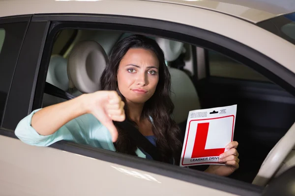 Woman gesturing thumbs down holding a learner driver sign - Stock Image ...