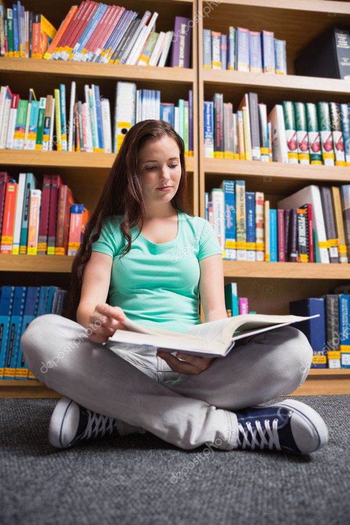 Student sitting on floor in library reading Stock Photo by ...