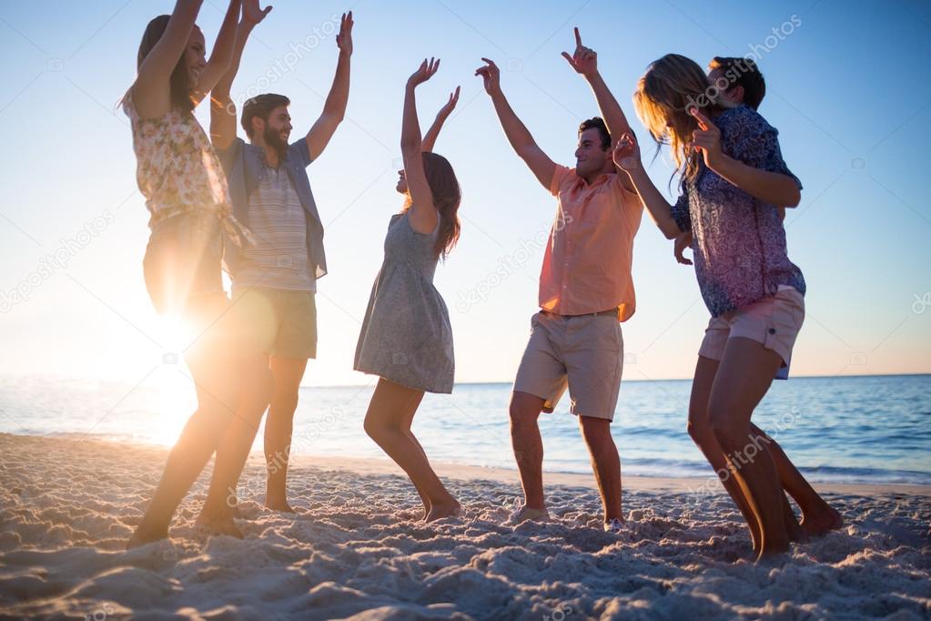 Happy friends dancing on the sand — Stock Photo © Wavebreakmedia #76353903
