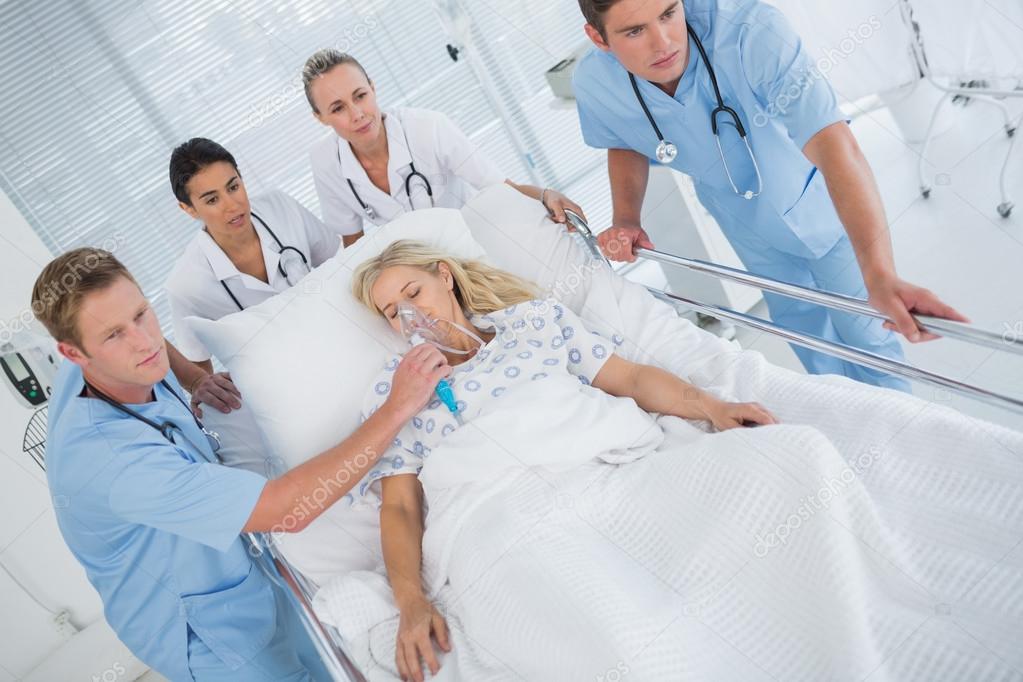 Team of doctors carrying patient on stretcher Stock Photo by ...
