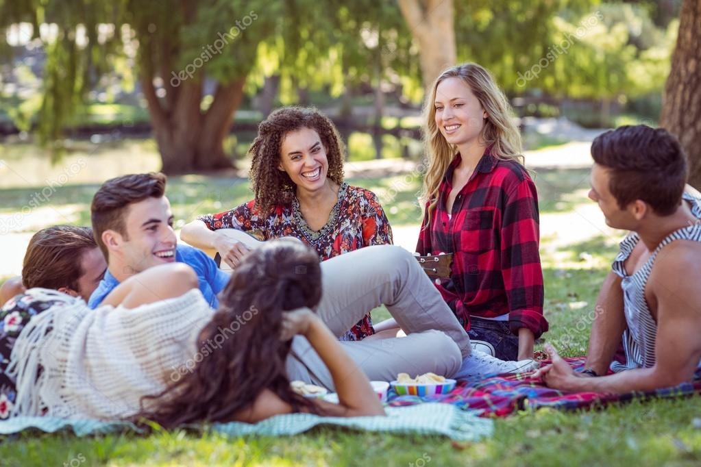 Happy friends in the park having picnic and playing guitar Stock Photo ...